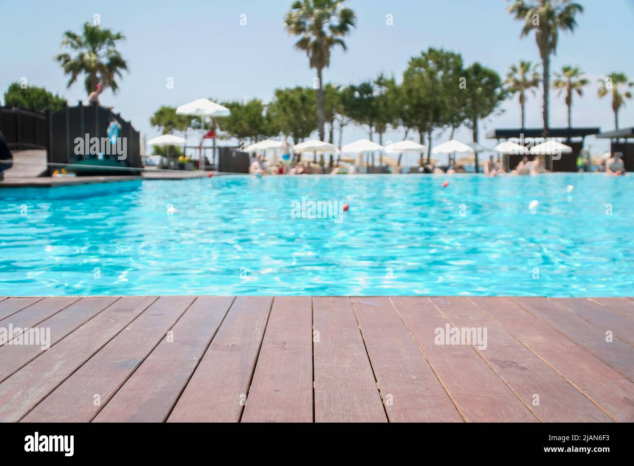 Wooden deck in front with blurred background of swimming pool in hotel ...