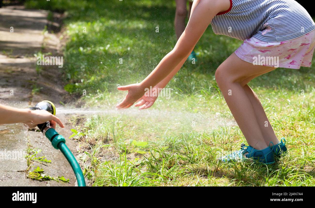 Anonymous child, school age girl playing with a water stream from a ...