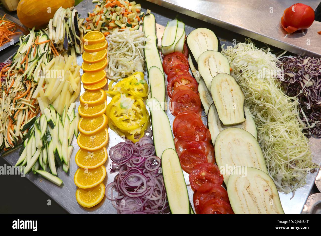 steel table with many vegetables cut by the cook for the preparation of ...