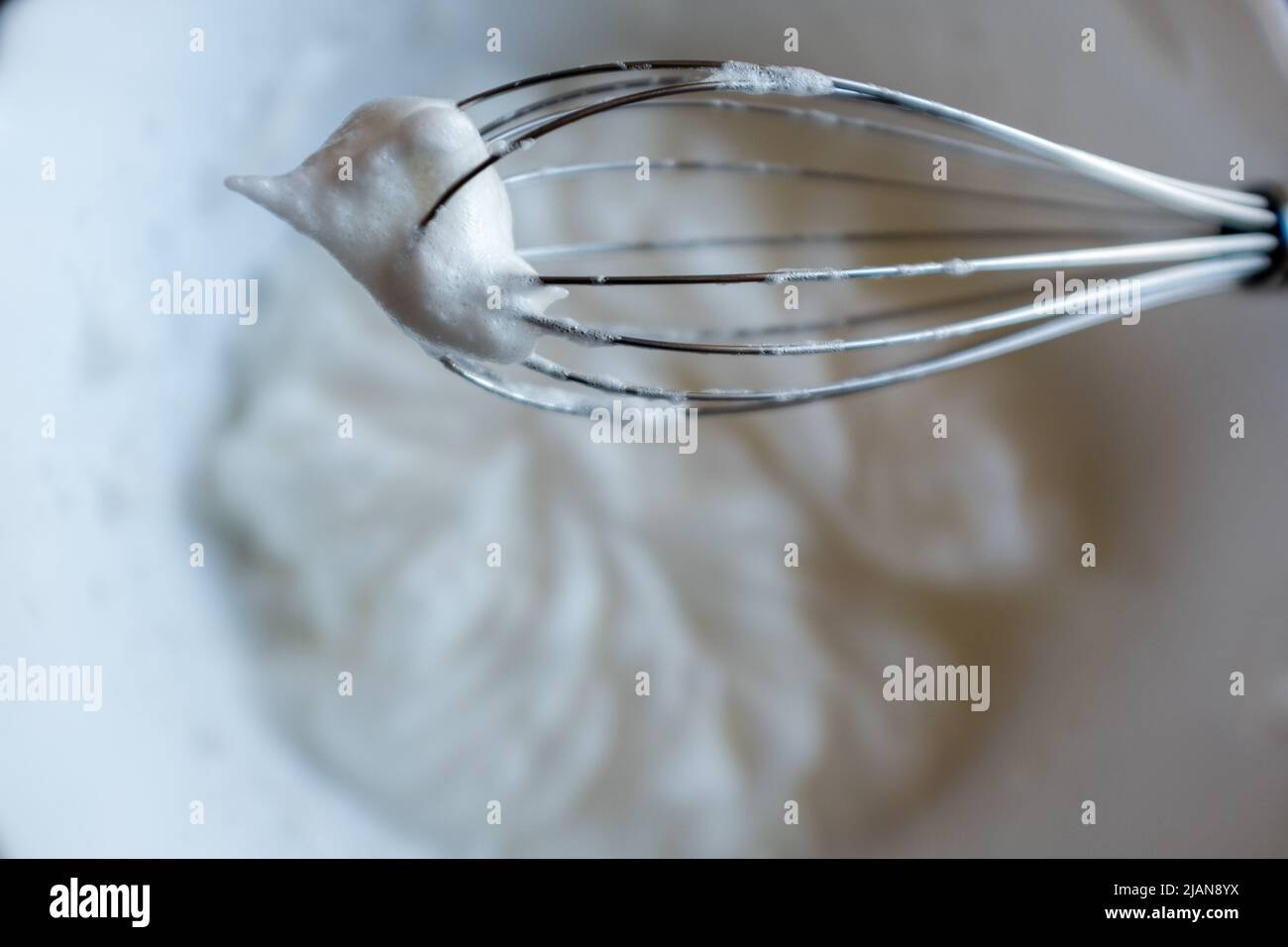 Whipped egg whites - beaten italian meringue on a whisk, closeup, copy ...