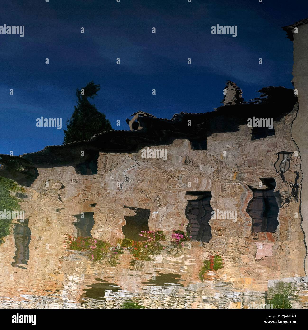 Square format view of honey-coloured stone buildings reflected in hot ...