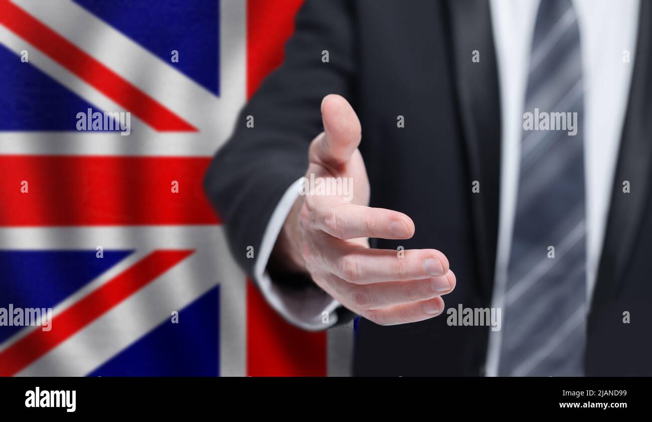 Welcome to the UK. Hand on flag background. Business, politics ...