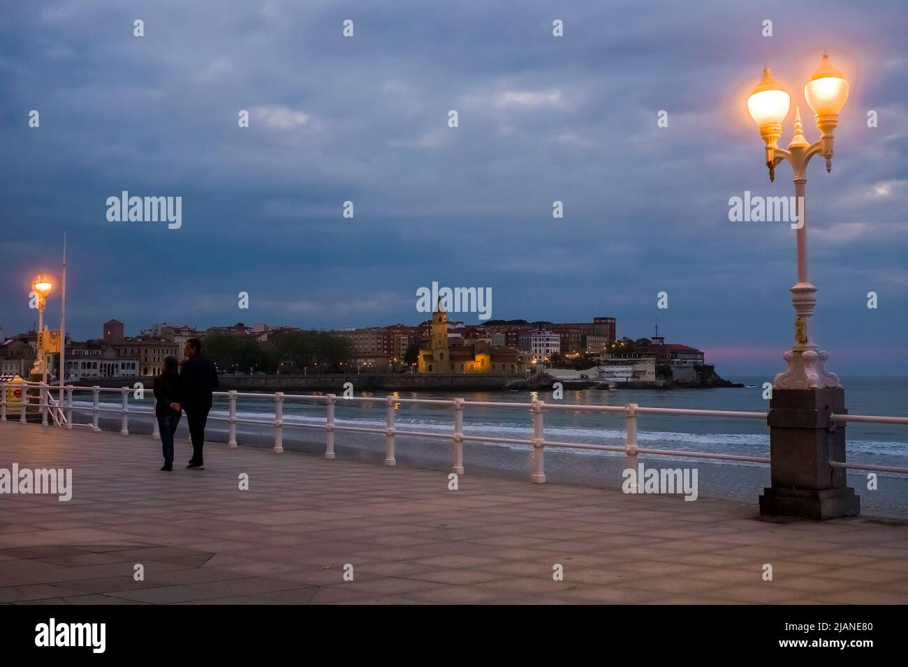 A couple walking down the promenade during the evening with the street ...