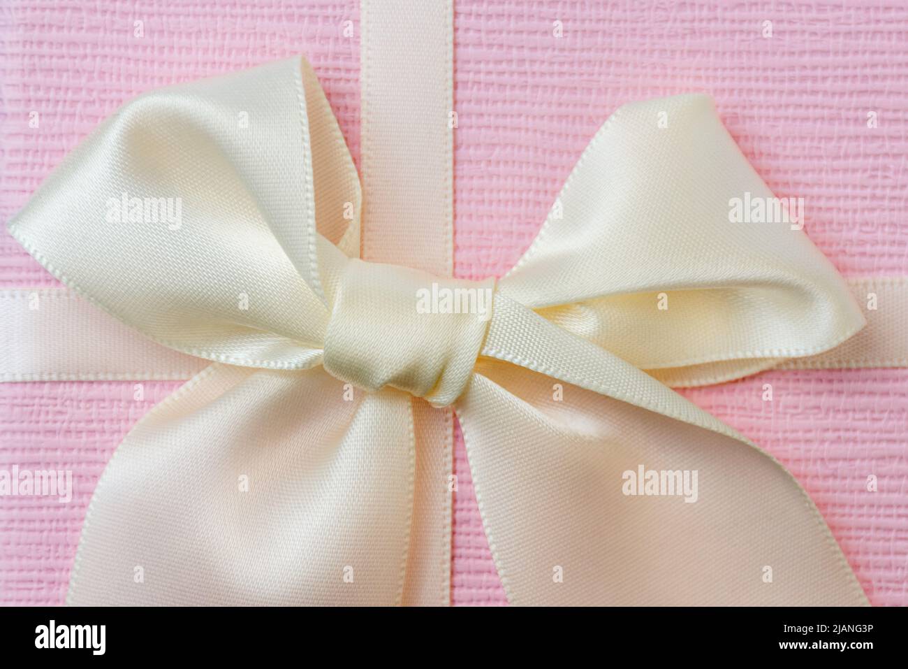 Close up of a beautiful bright bow with satin ribbon on a pink gift box ...