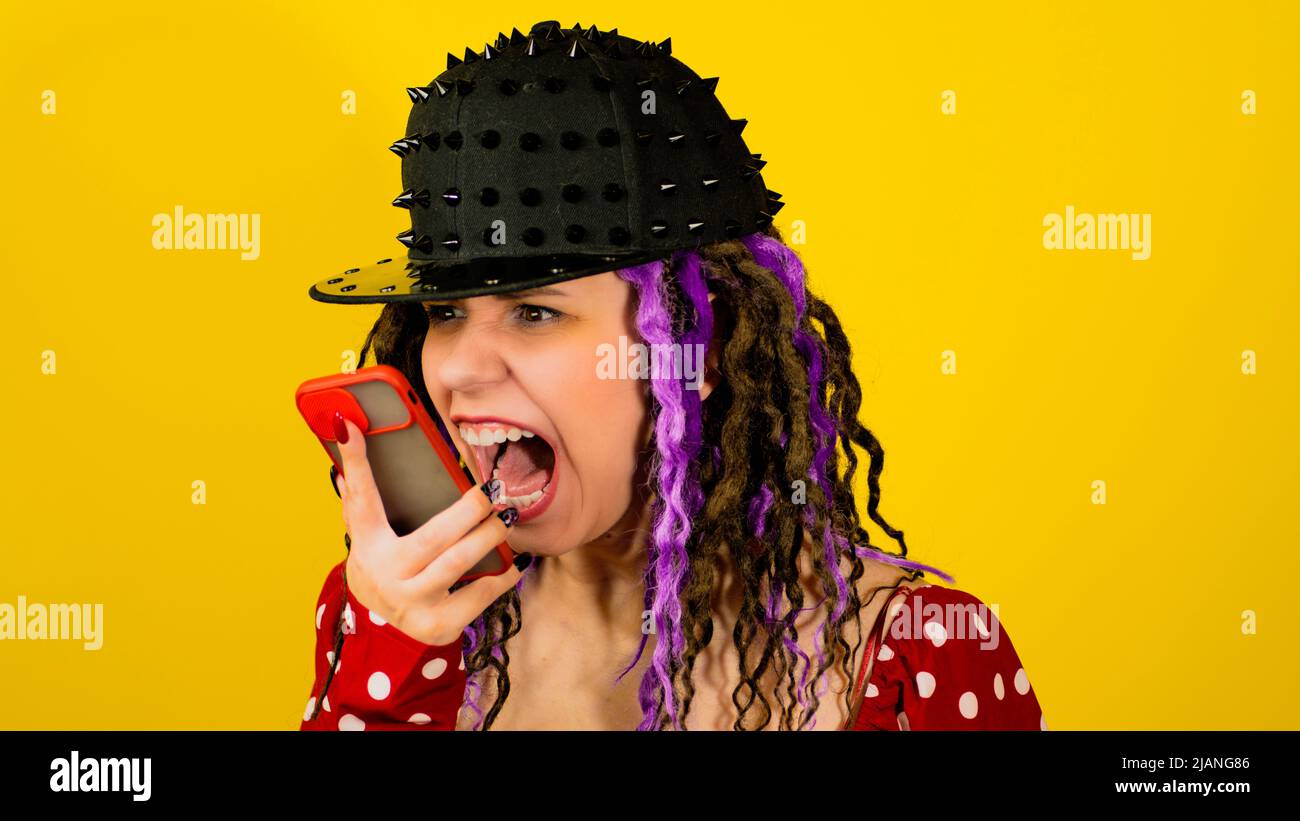 Young aggressive woman shouts into mobile phone. Angry excited girl ...