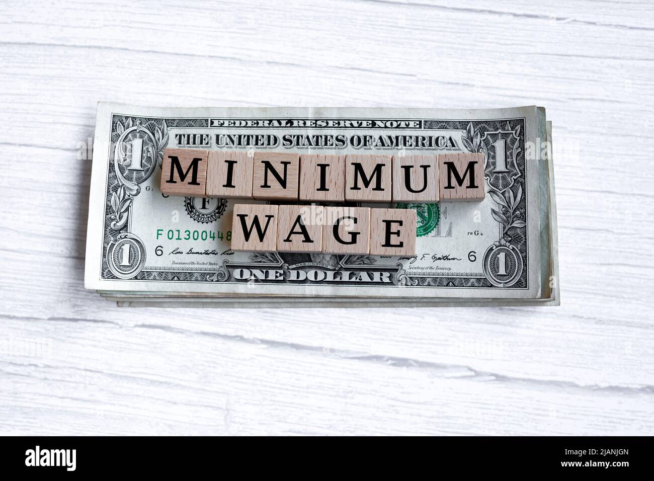 Minimum wage word written on wood block with American Dollar-bills ...
