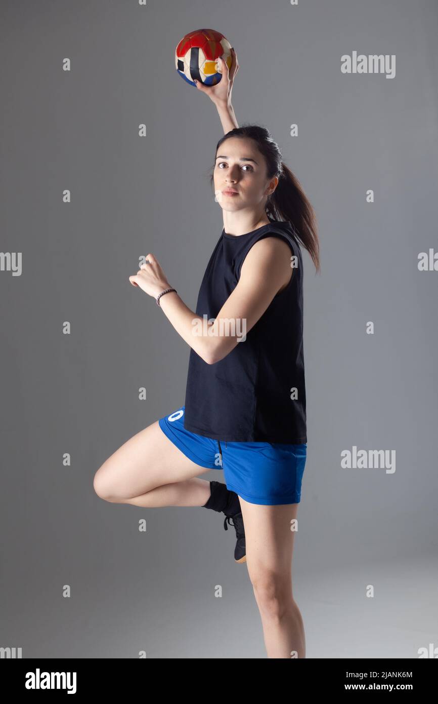Handball player posing on light gray background. Girl jumping with ball ...