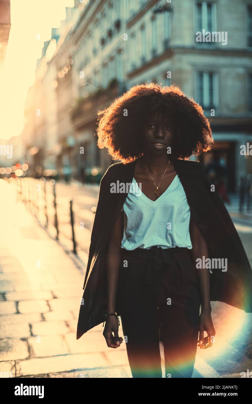 A young dazzling black female with fluffy afro hair, in a coat, slung ...