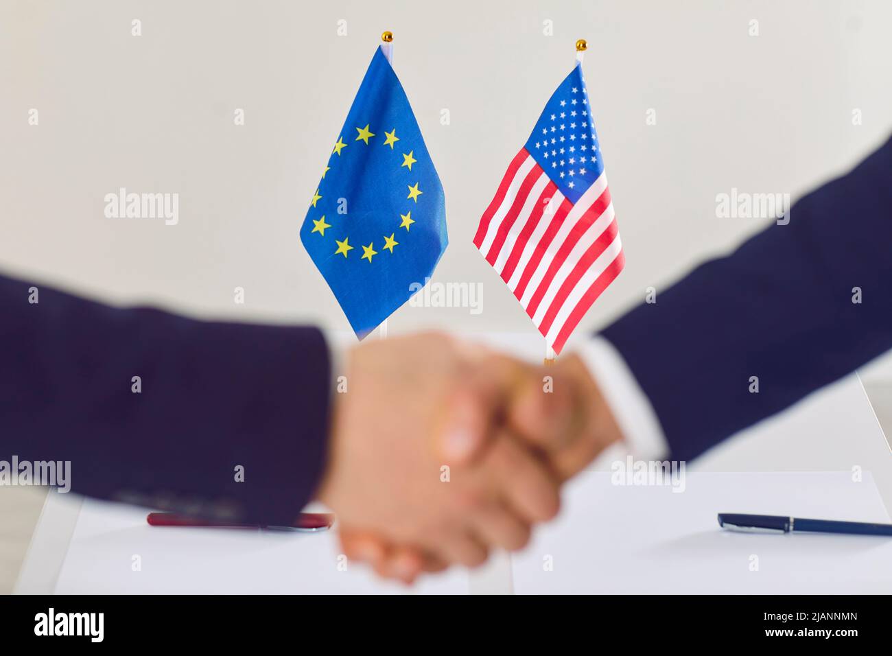 Small flags of America and European Union during handshake that ...
