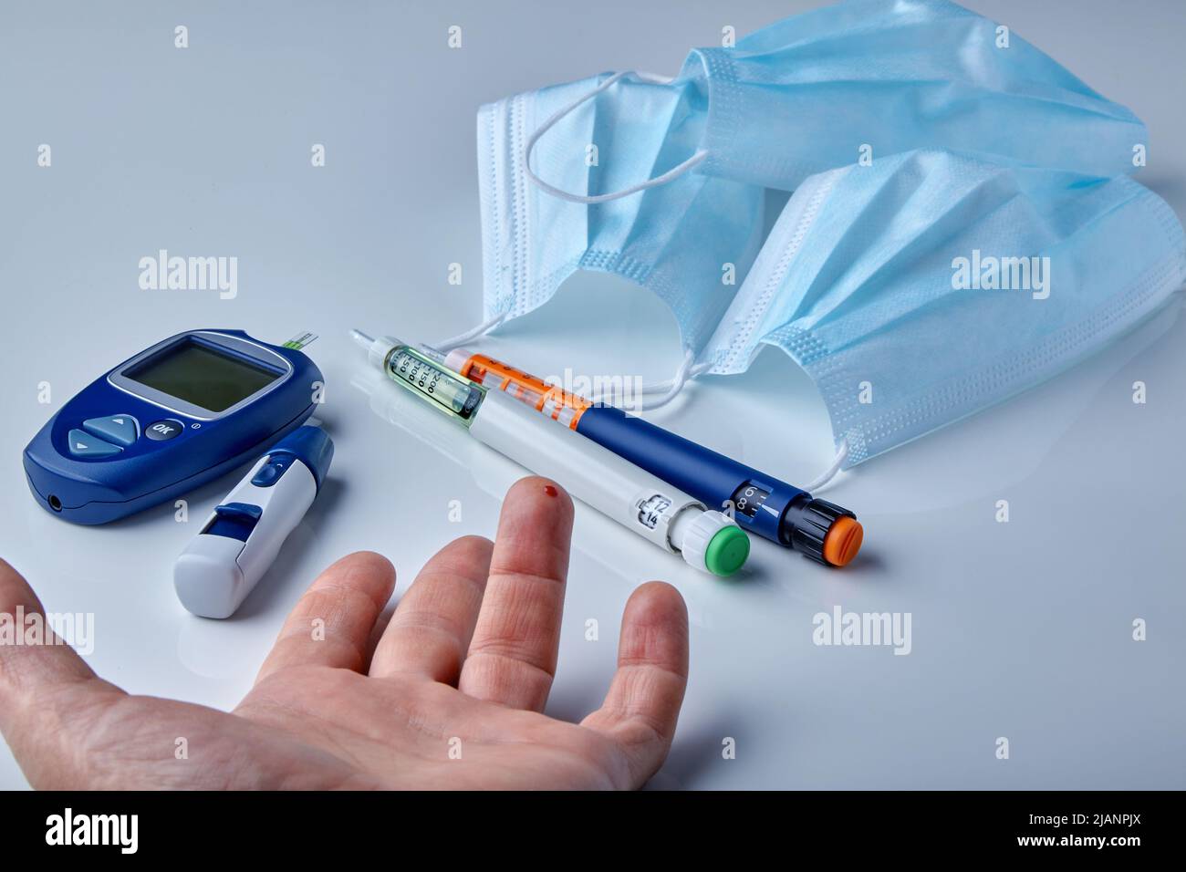 Male hand with a drop of blood on a finger, a glucometer, insulin ...