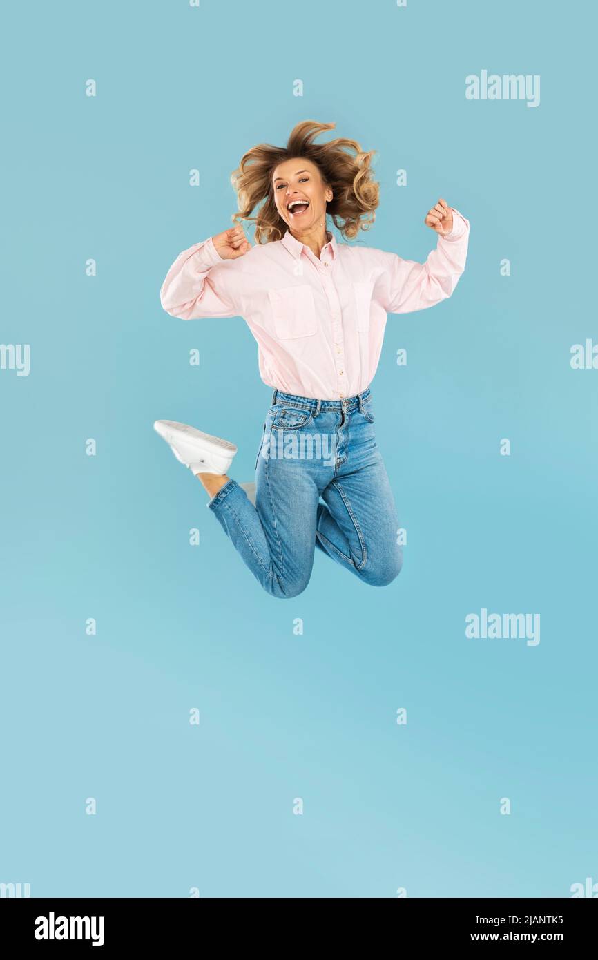 Joyful Lady Jumping Having Fun In Mid Air, Blue Background Stock Photo ...