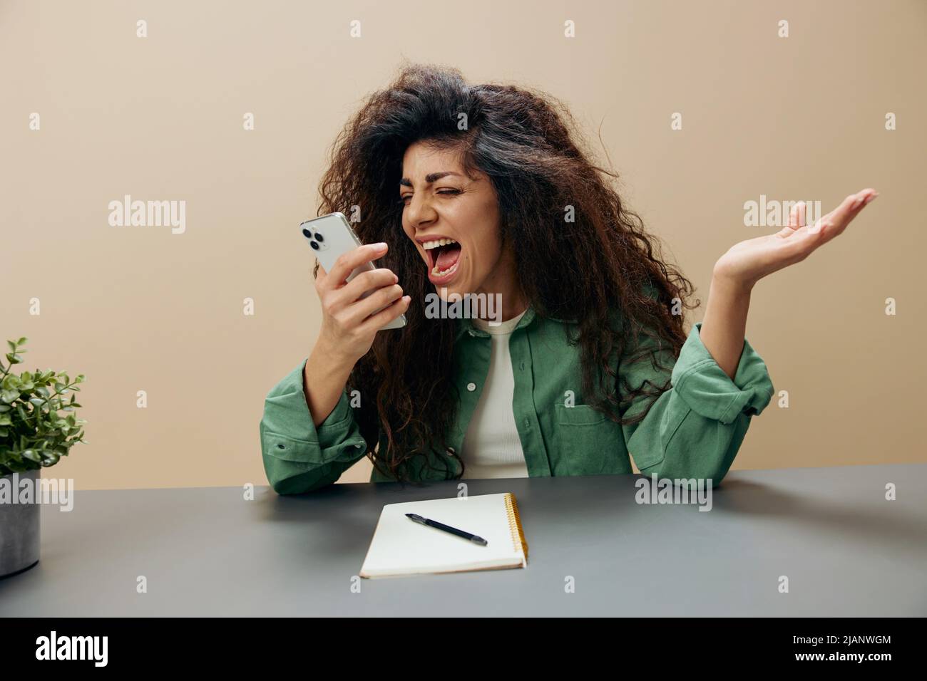 Angry crazy irritated tanned curly Latin lady scream at phone screen ...