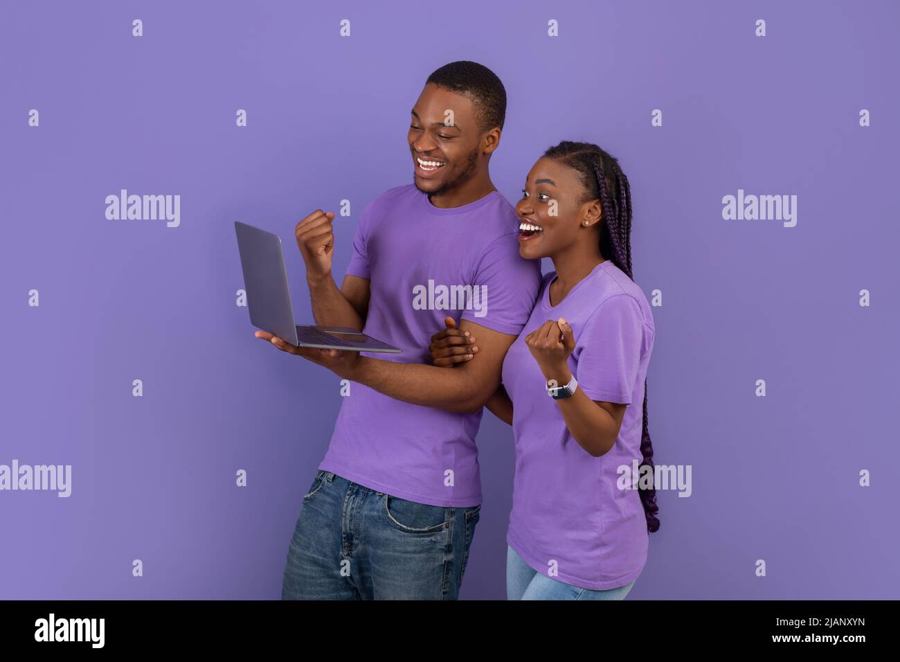 Black couple using laptop celebrating success shaking fists Stock Photo ...