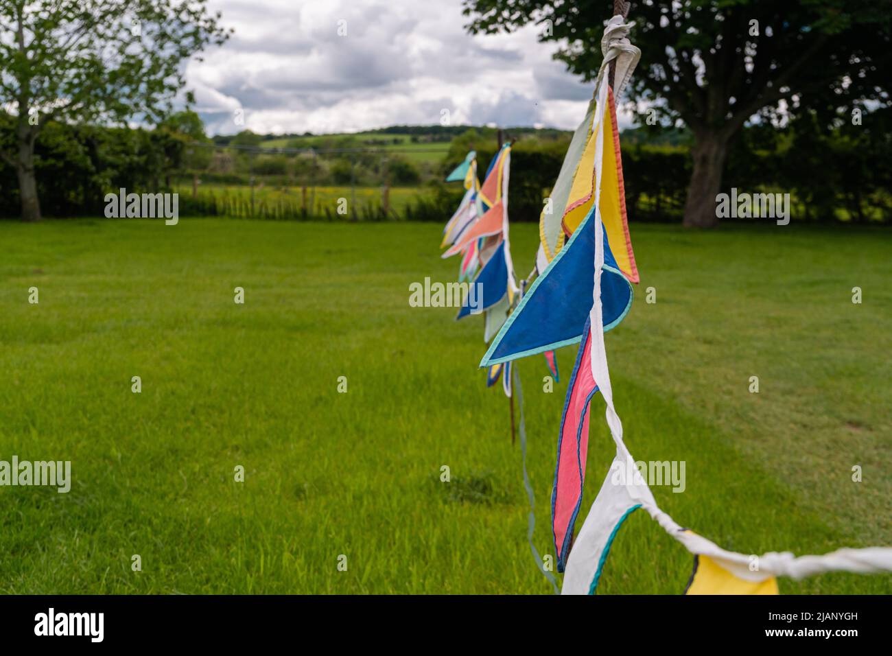 Colorful bunting flying with the wind on green grass field in spring ...