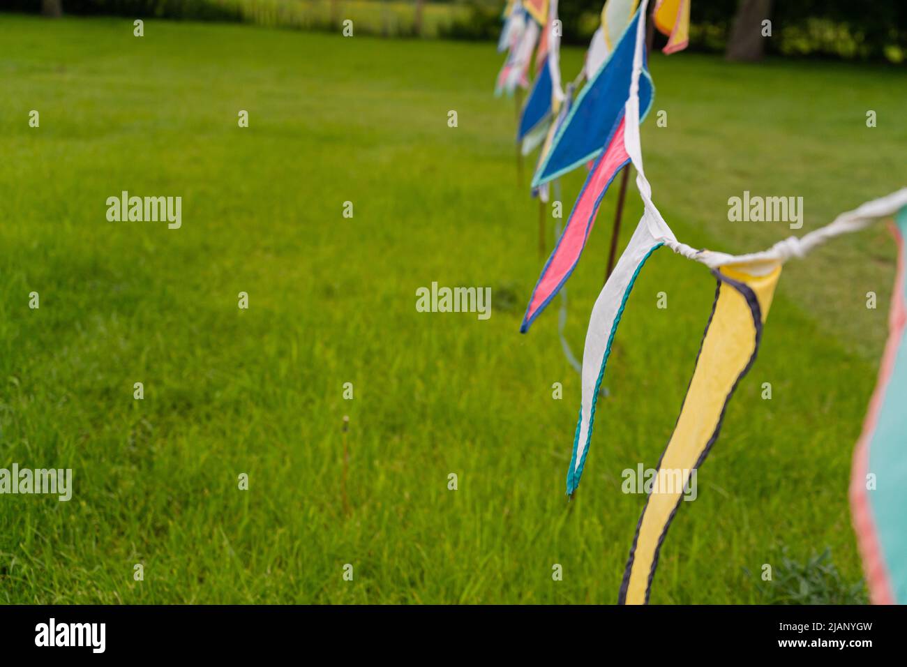 Colorful bunting flying with the wind on green grass field in spring ...