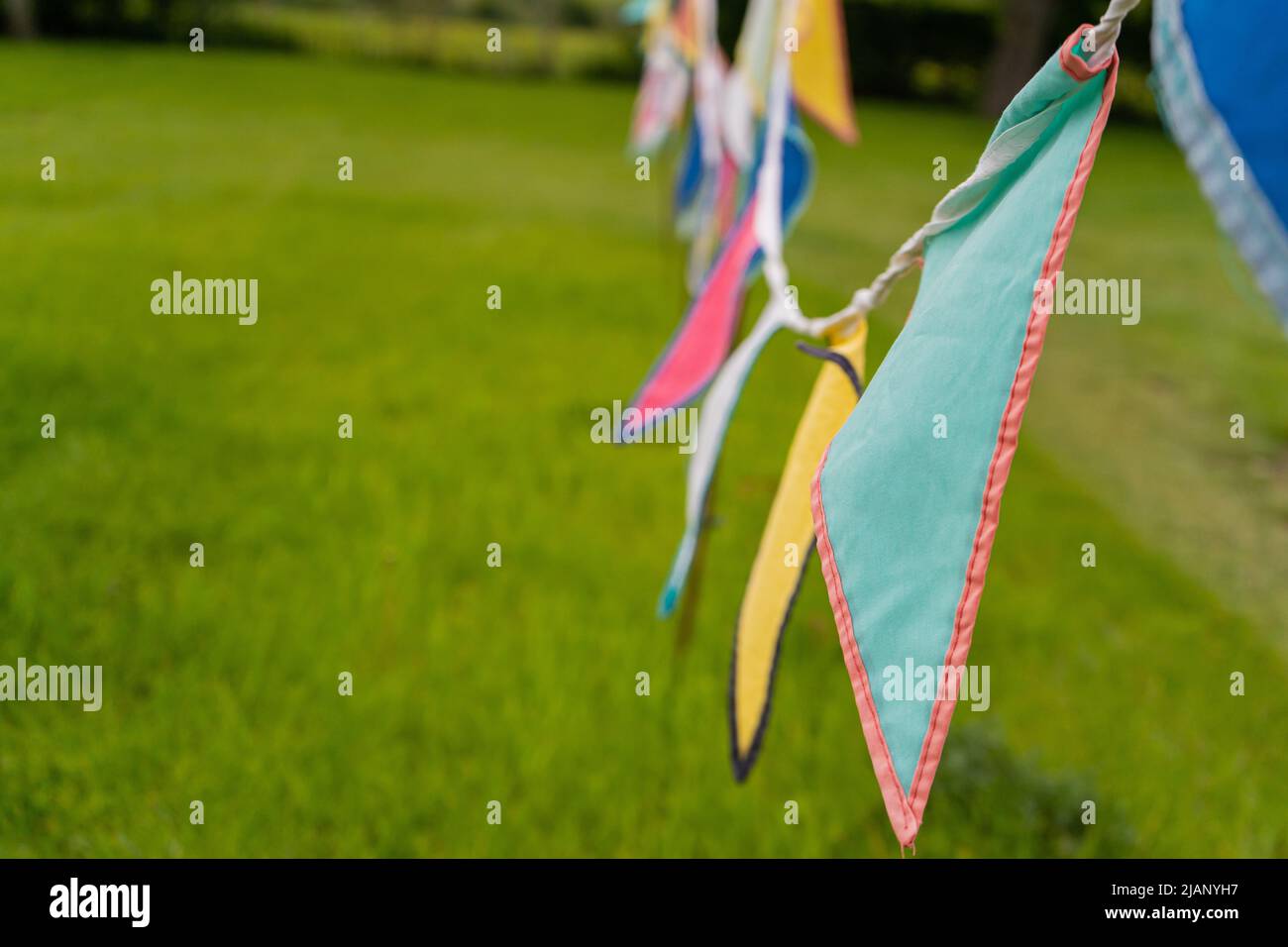 Colorful bunting flying with the wind on green grass field in spring ...