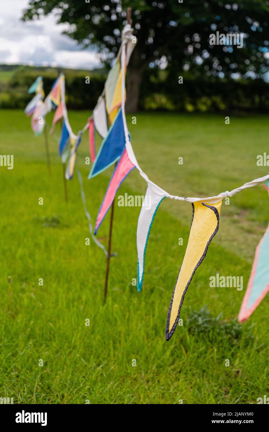 Colorful bunting flying with the wind on green grass field in spring ...