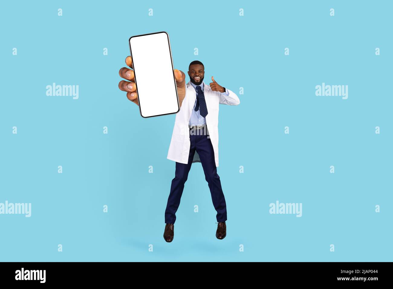 Online Doctor. Black Therapist In Uniform Jumping With Blank Smartphone ...