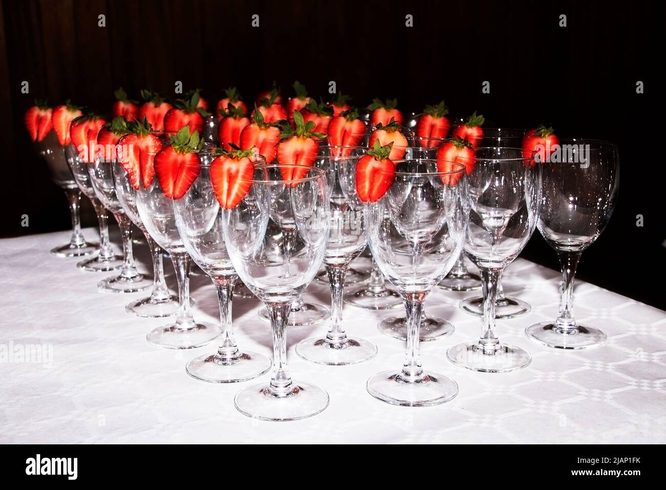 rows of champagne glasses decorated with red strawberries at the buffet ...