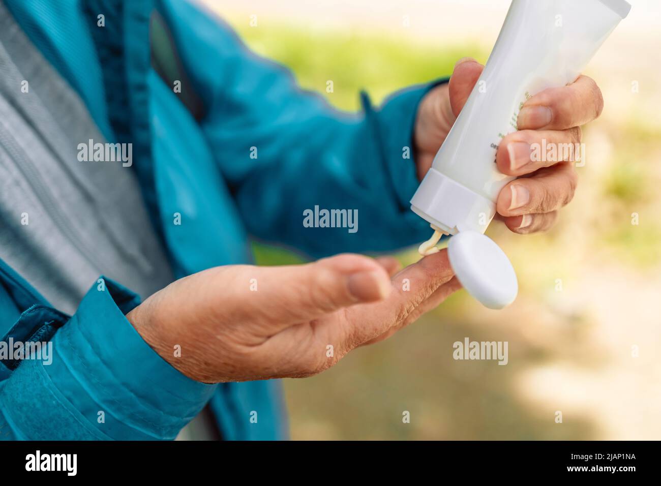 Caucasian woman hands applying sunscreen lotion from a white tube while ...