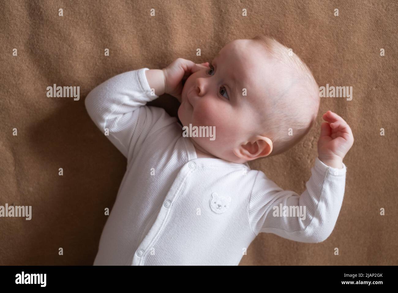 happy caucasian nine months old baby girl looking at camera during home ...