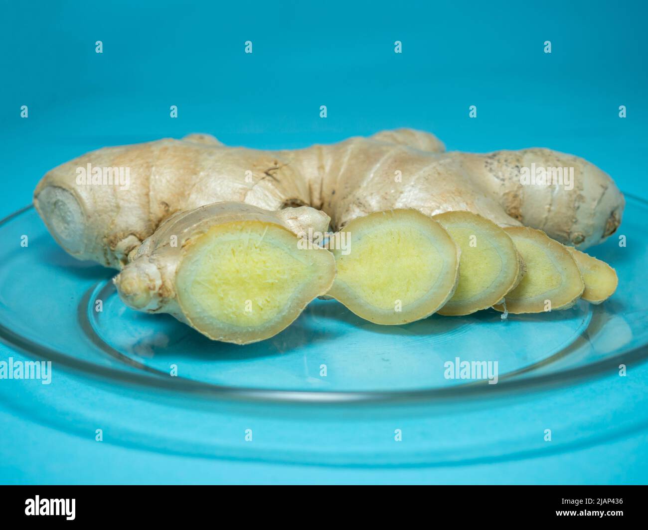 Cut ginger root on a transparent plate. Blue background Stock Photo - Alamy