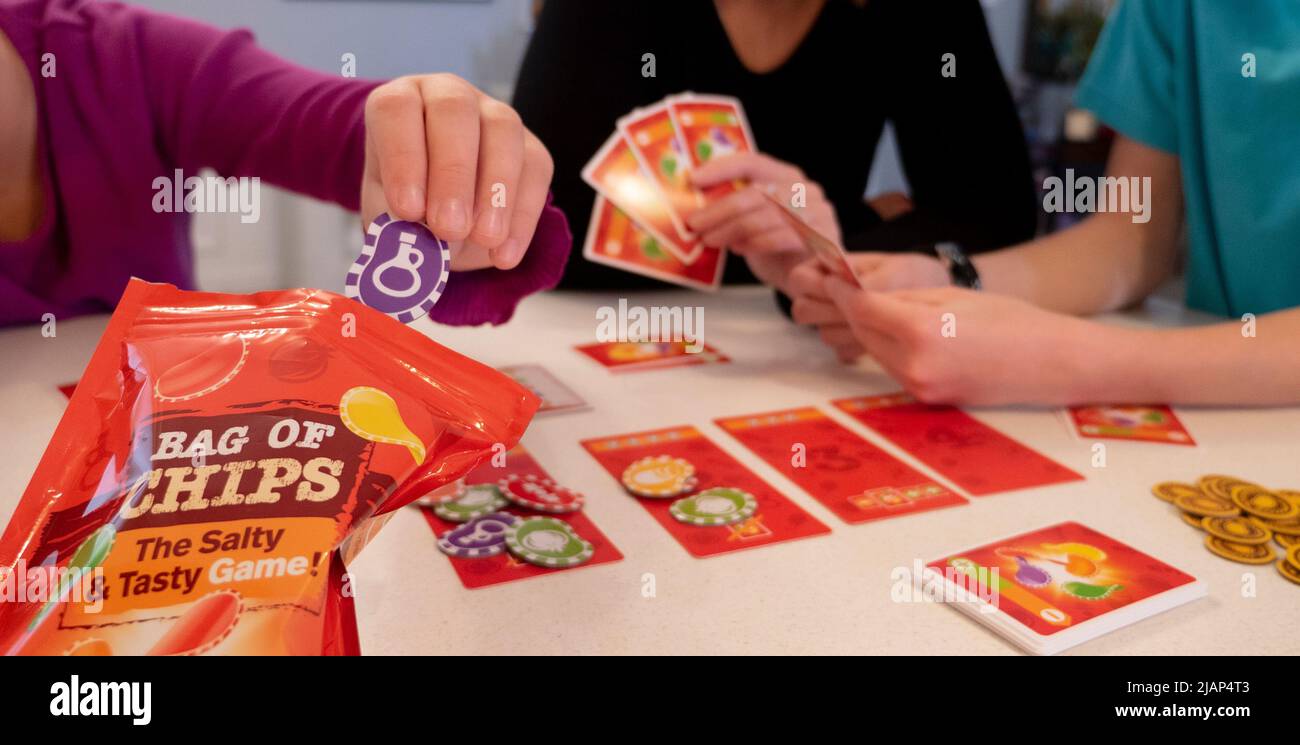 Family playing brand new "chip themed" card game at the kitchen counter ...
