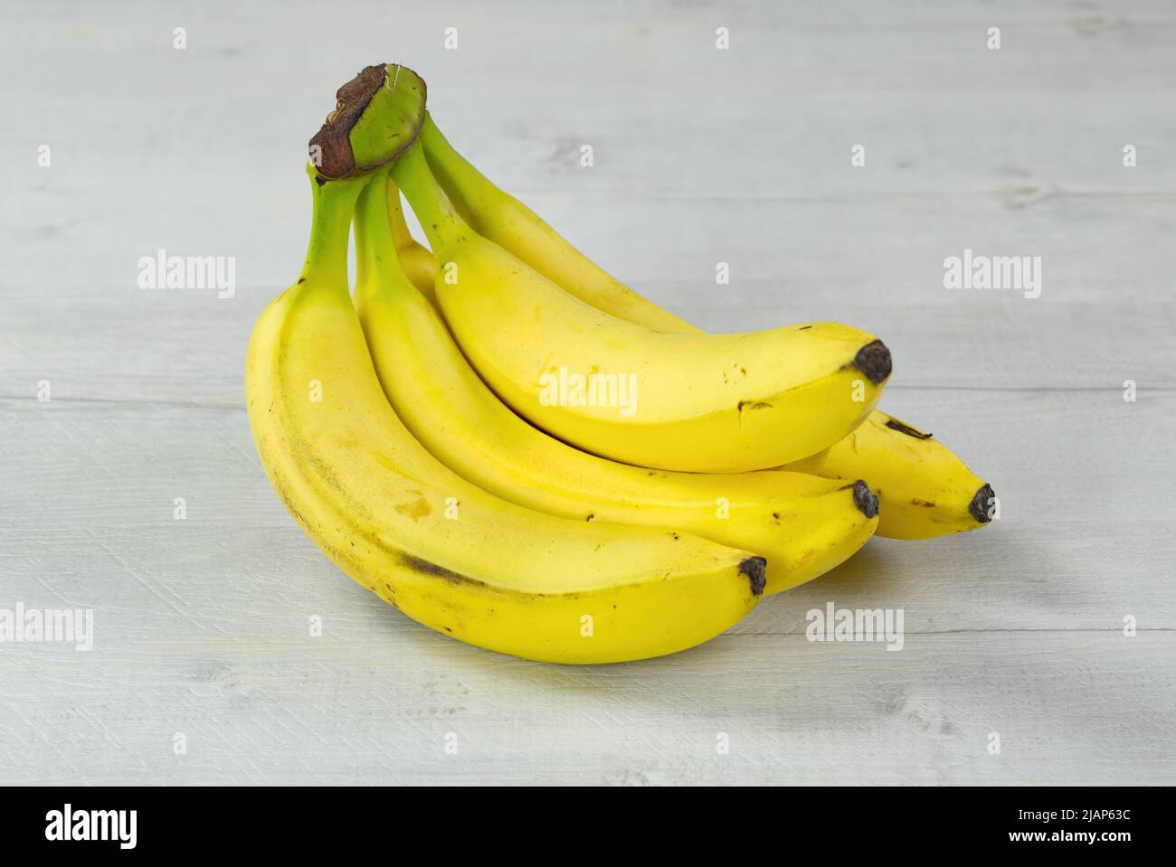 Banana bunch on a light wooden background Stock Photo - Alamy