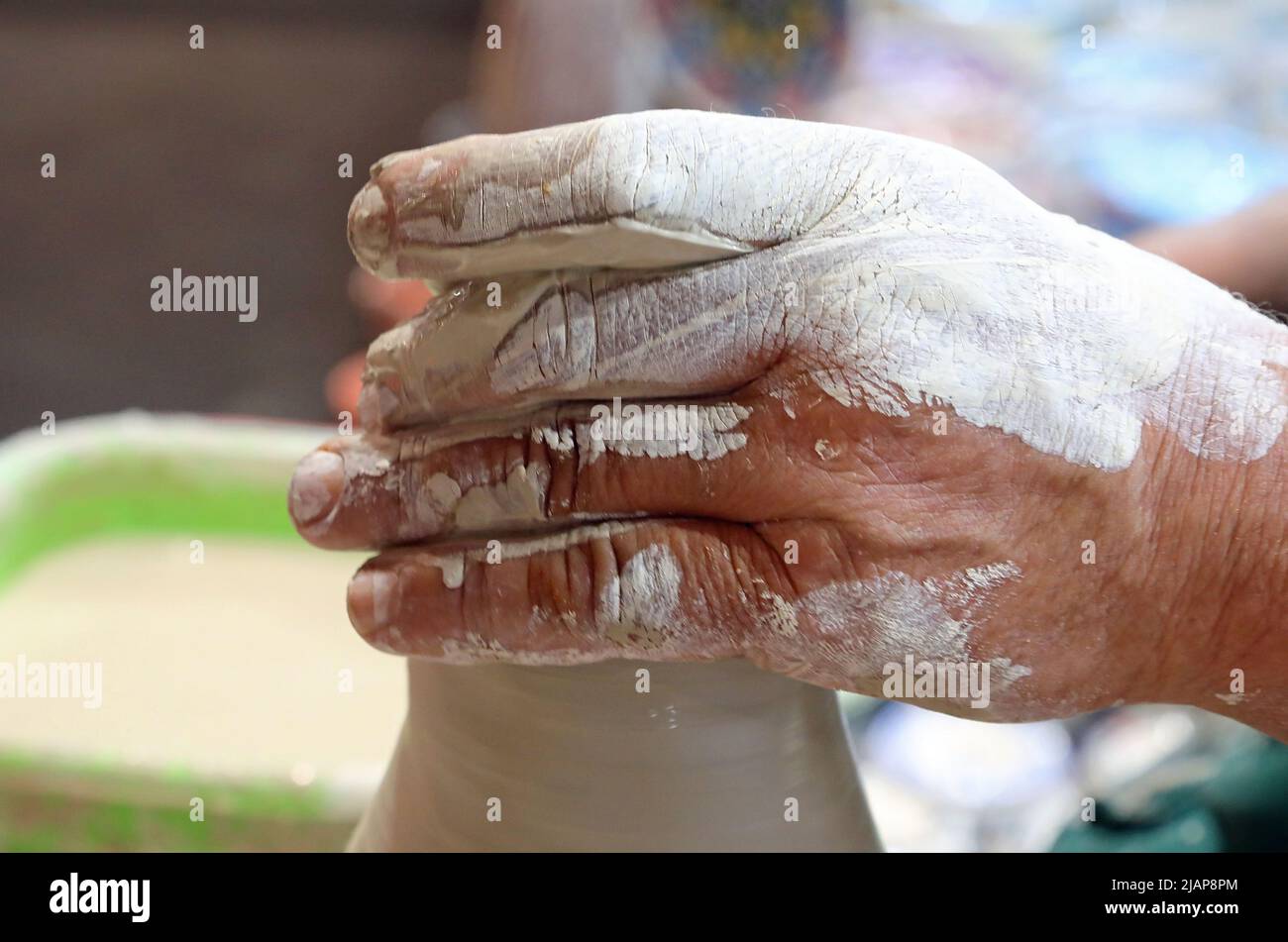 hand of the expert potter as he shapes a clay pot using light pressure ...