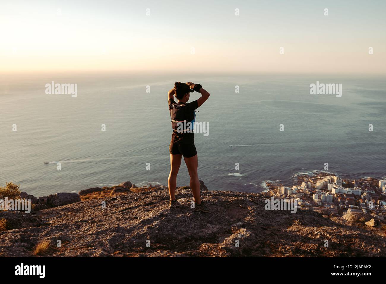 Rear view of young woman looking on the ocean from mountain top after ...