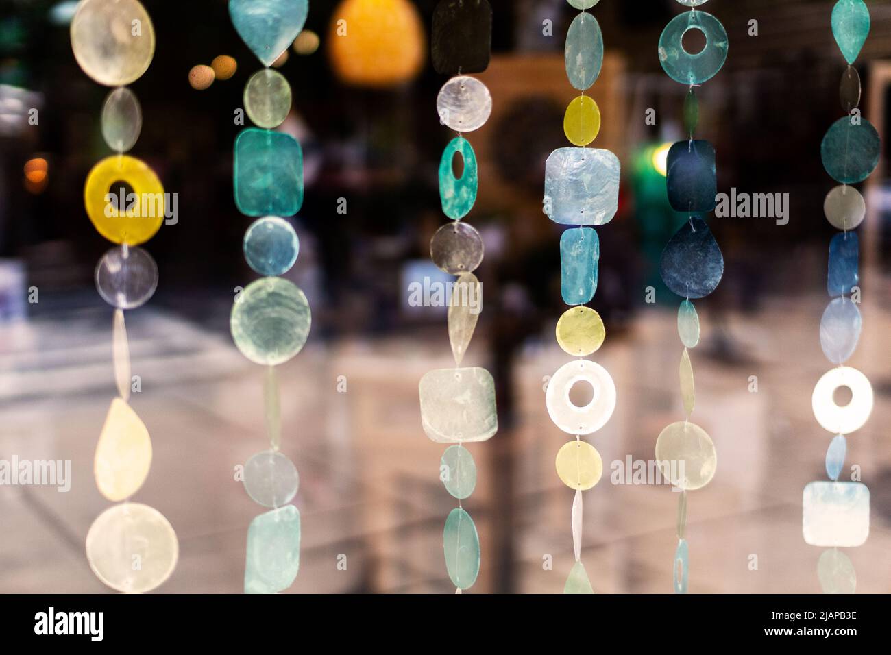 A wall hanging of geometric shapes on string hangs in the window of a ...