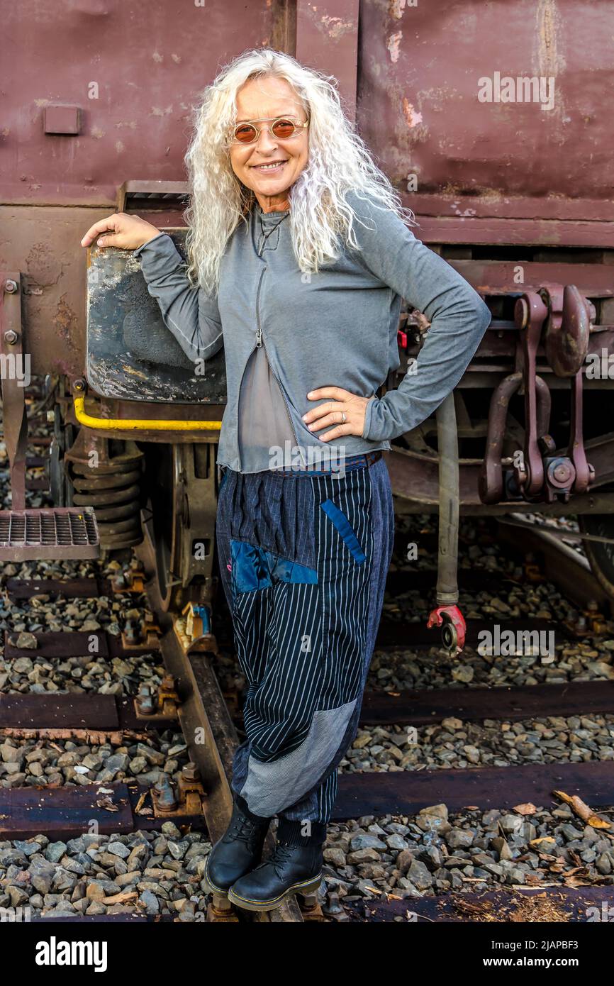 Beautiful Lady in the 50s standing in front of industry freight train ...