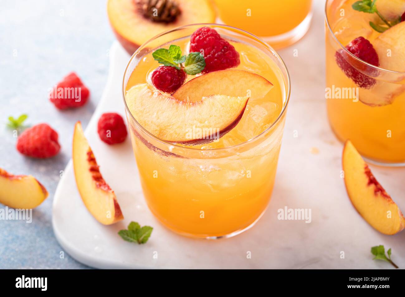Refreshing summer cocktail with peach and raspberry Stock Photo - Alamy