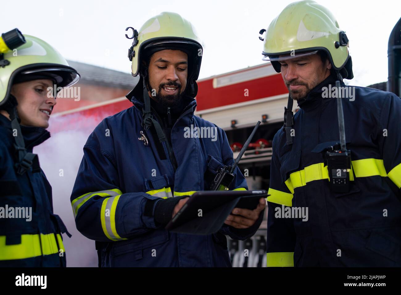 Happy firefighters crew with fire station and truck in background Stock ...