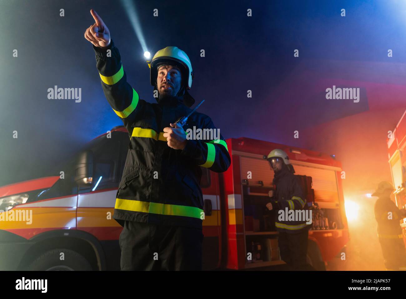 Firefighter talking to walkie talkie with fire truck in background at ...