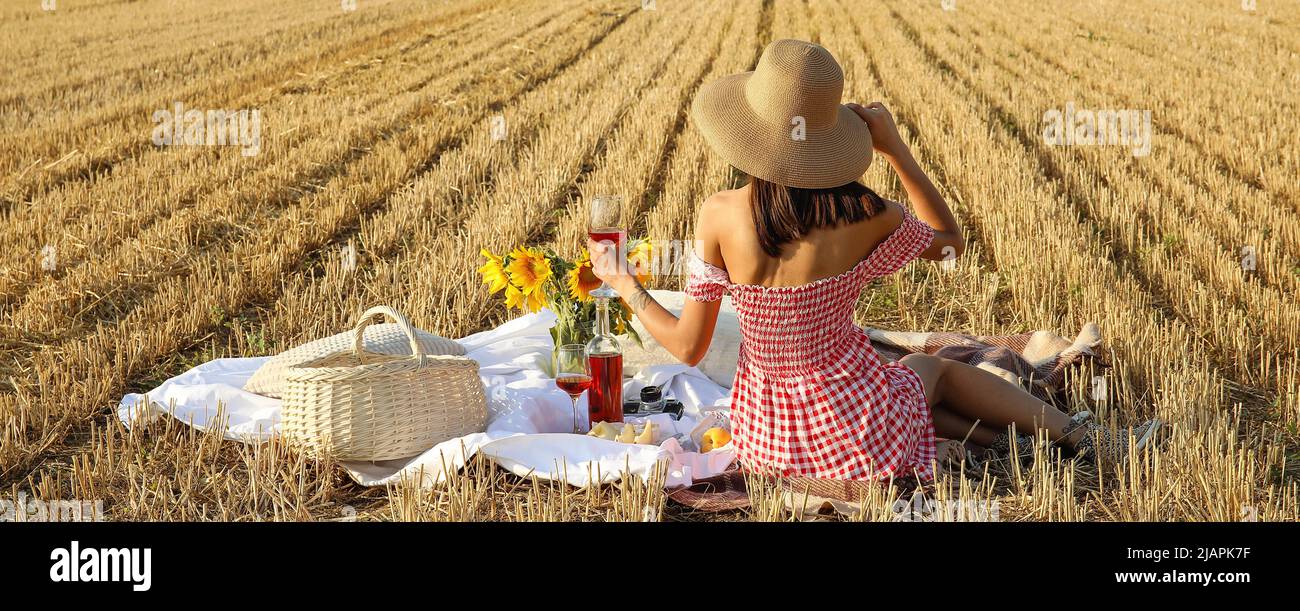Pretty young woman having picnic in field Stock Photo - Alamy