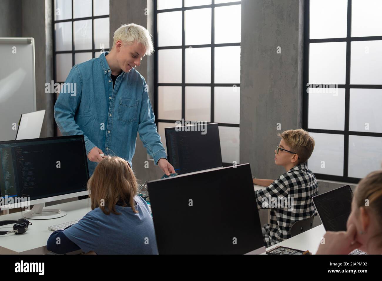 School kids with help of teacher using computer in classroom at school ...