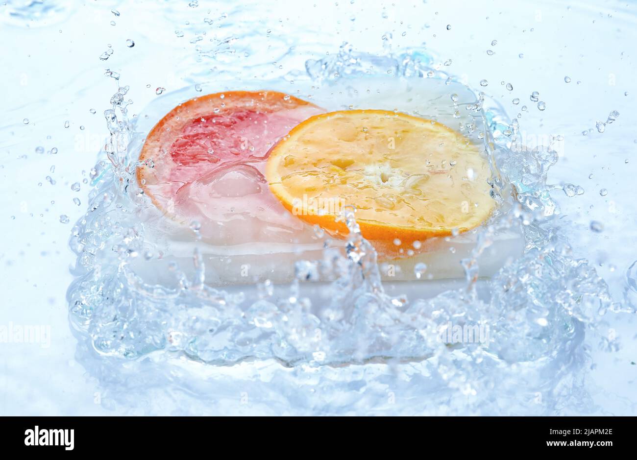 Fresh slices of citrus fruits frozen in ice with water splash on white ...