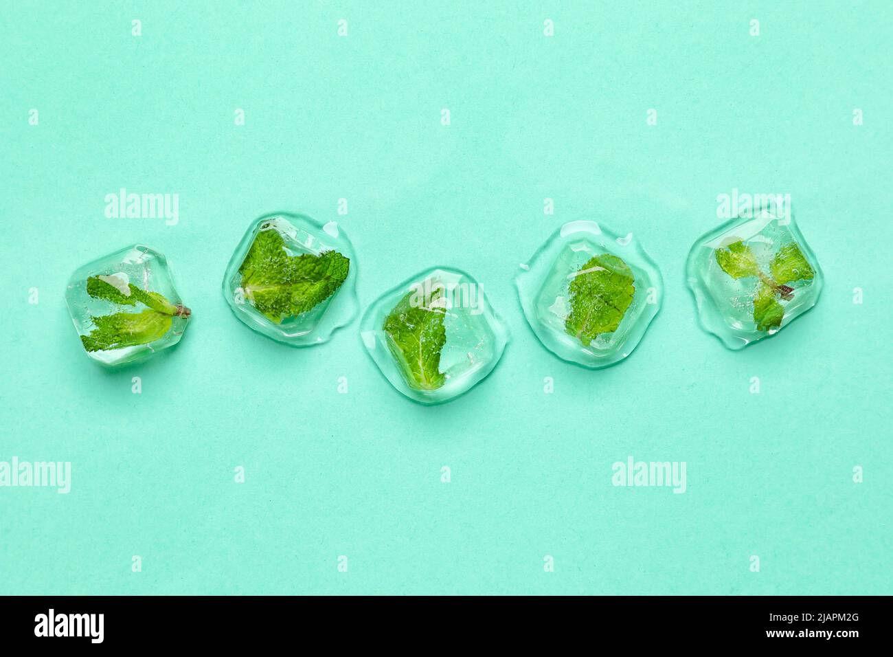 Fresh mint leaves frozen in ice on turquoise background Stock Photo - Alamy