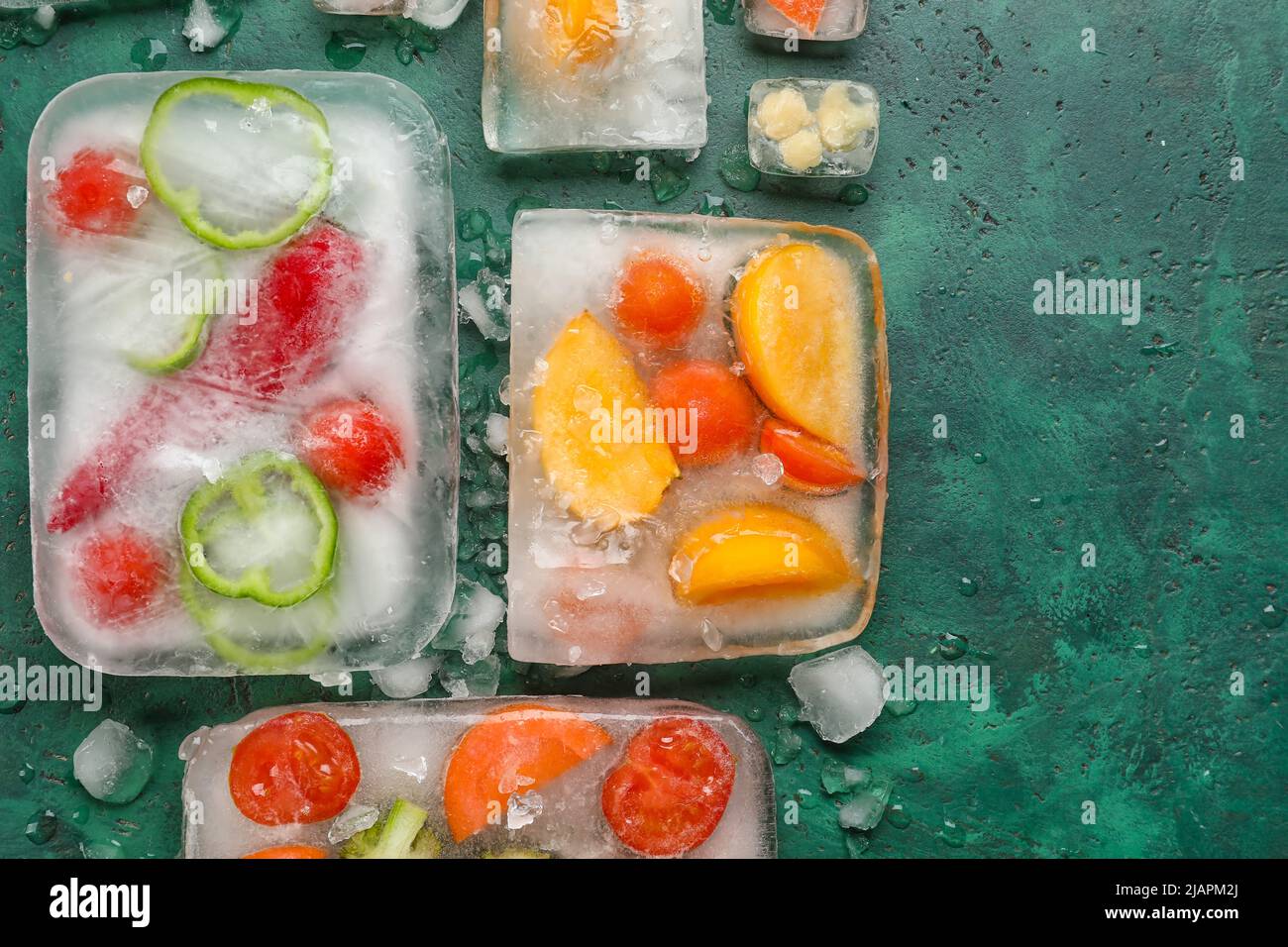 Fresh cut vegetables frozen in ice on green background Stock Photo - Alamy