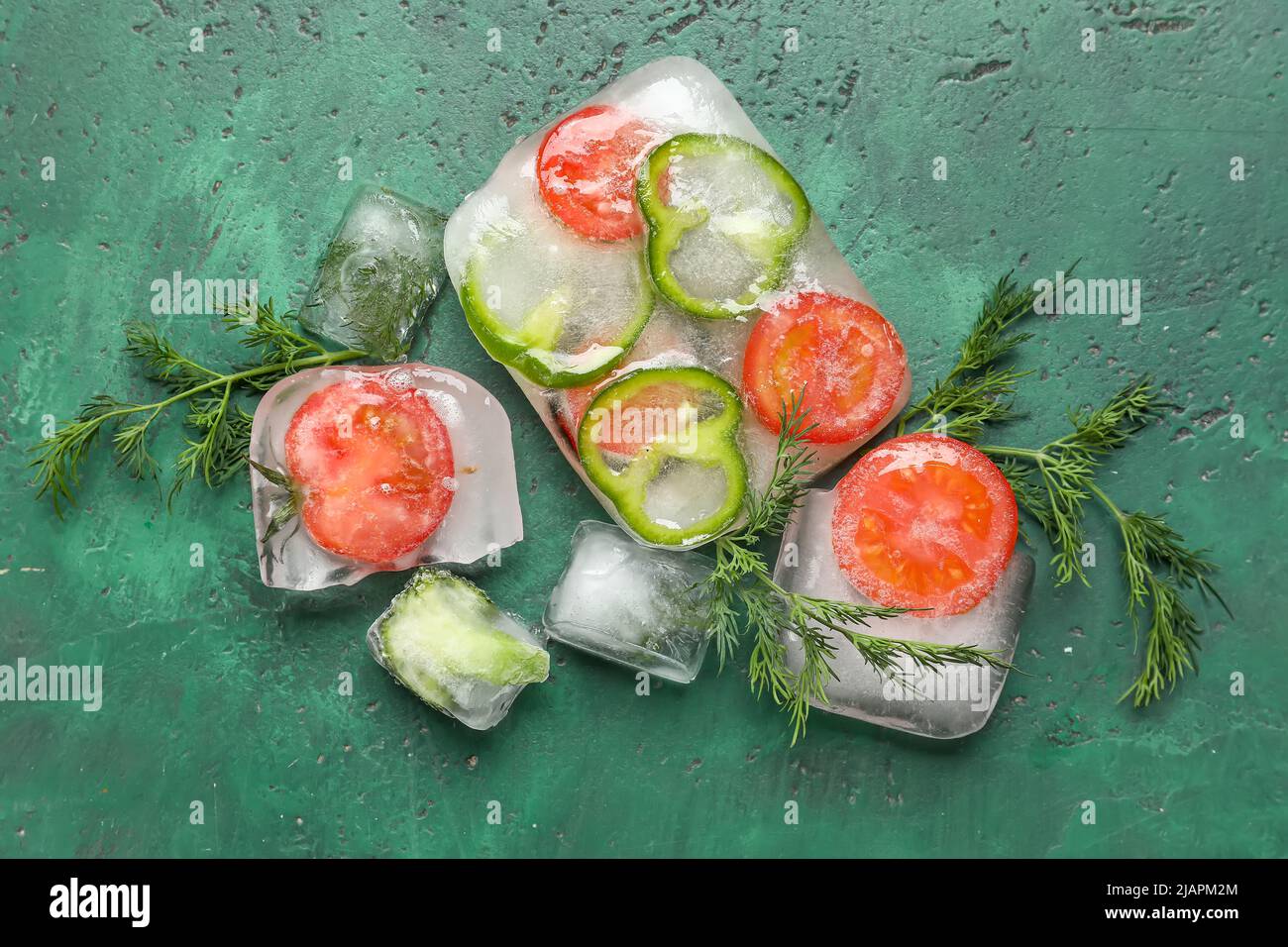 Fresh cut vegetables frozen in ice on green background Stock Photo - Alamy