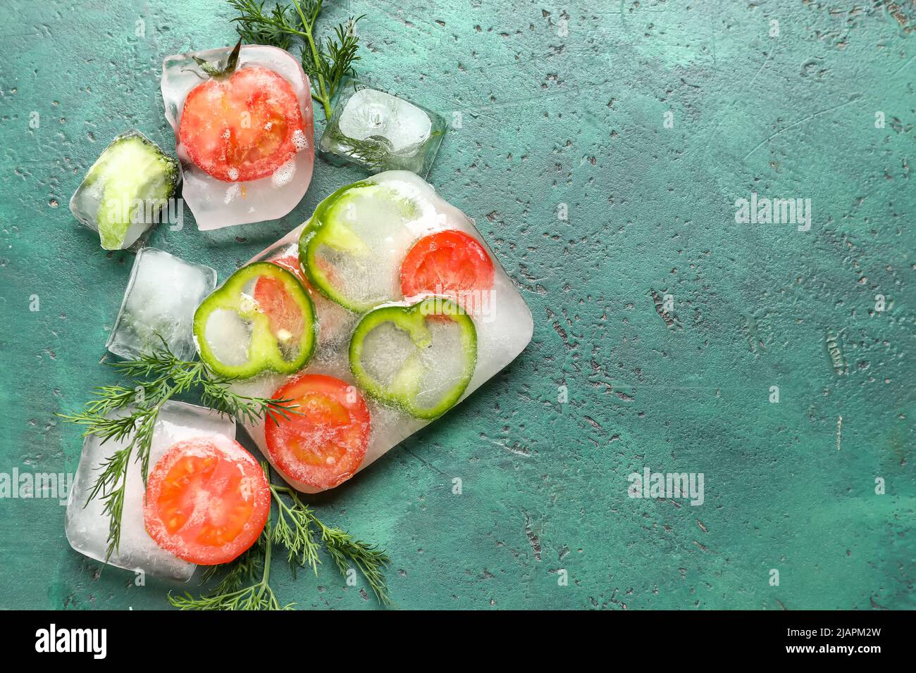 Fresh cut vegetables frozen in ice on green background Stock Photo - Alamy