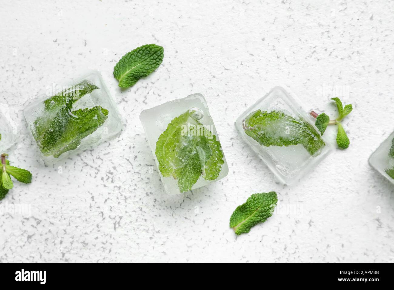 Fresh mint leaves frozen in ice on light background Stock Photo - Alamy