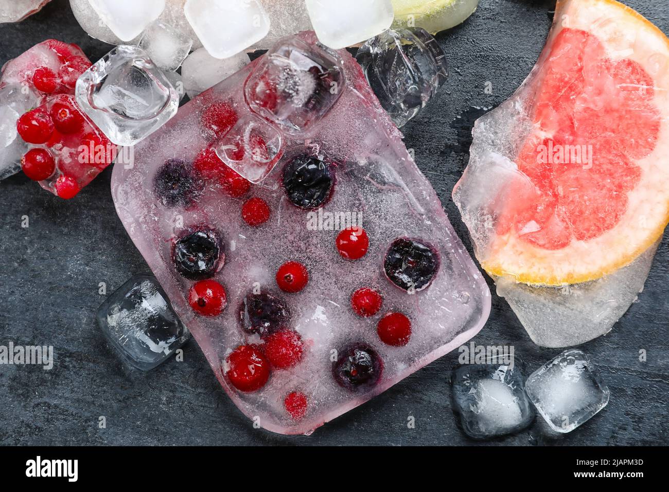 Fresh fruits frozen in ice on black background Stock Photo - Alamy