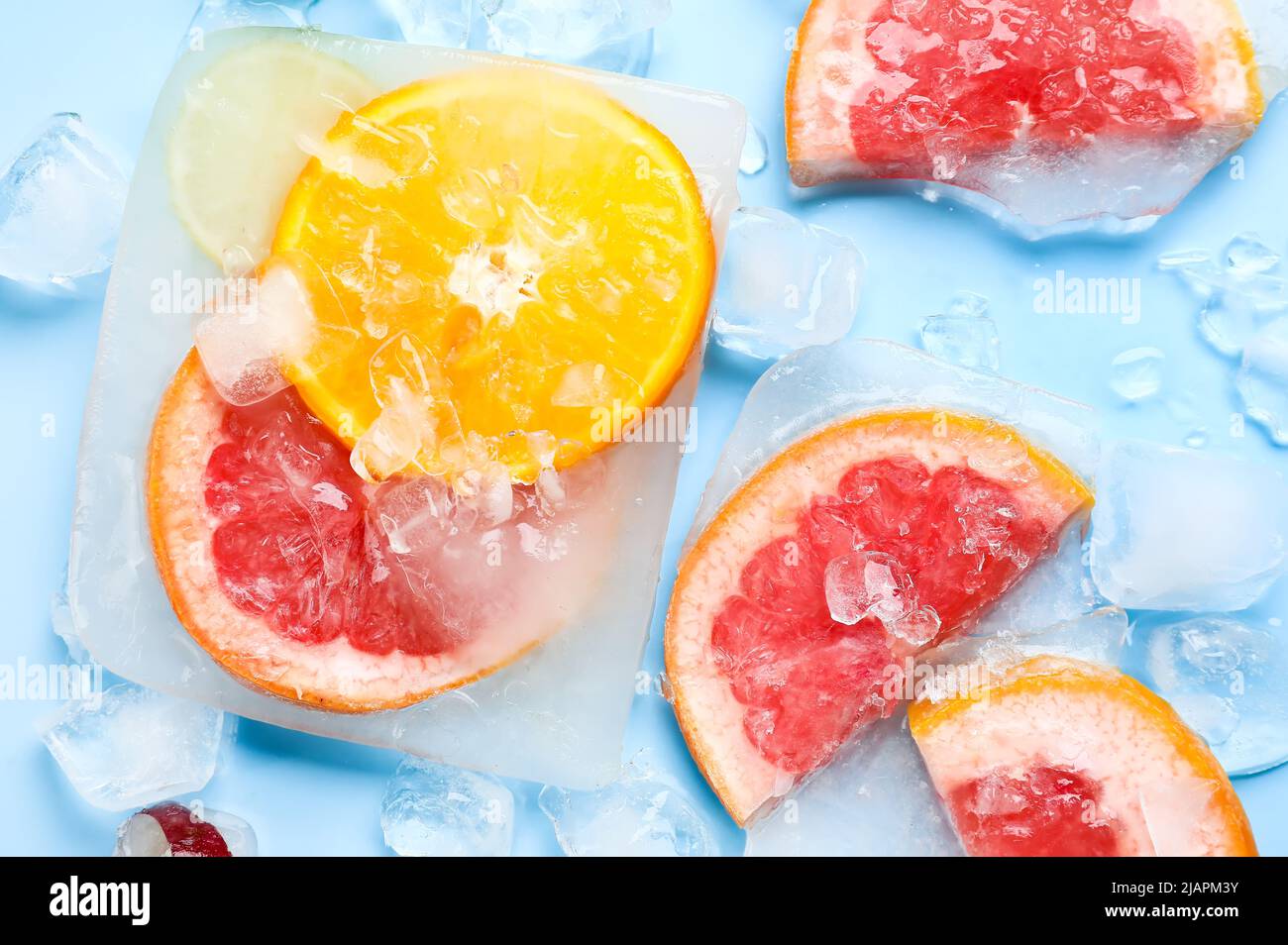 Fresh slices of citrus fruits frozen in ice on blue background Stock ...