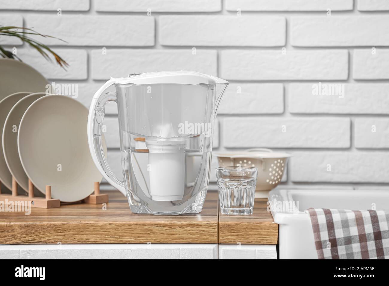 Filter jug and glass of water on counter in kitchen Stock Photo - Alamy