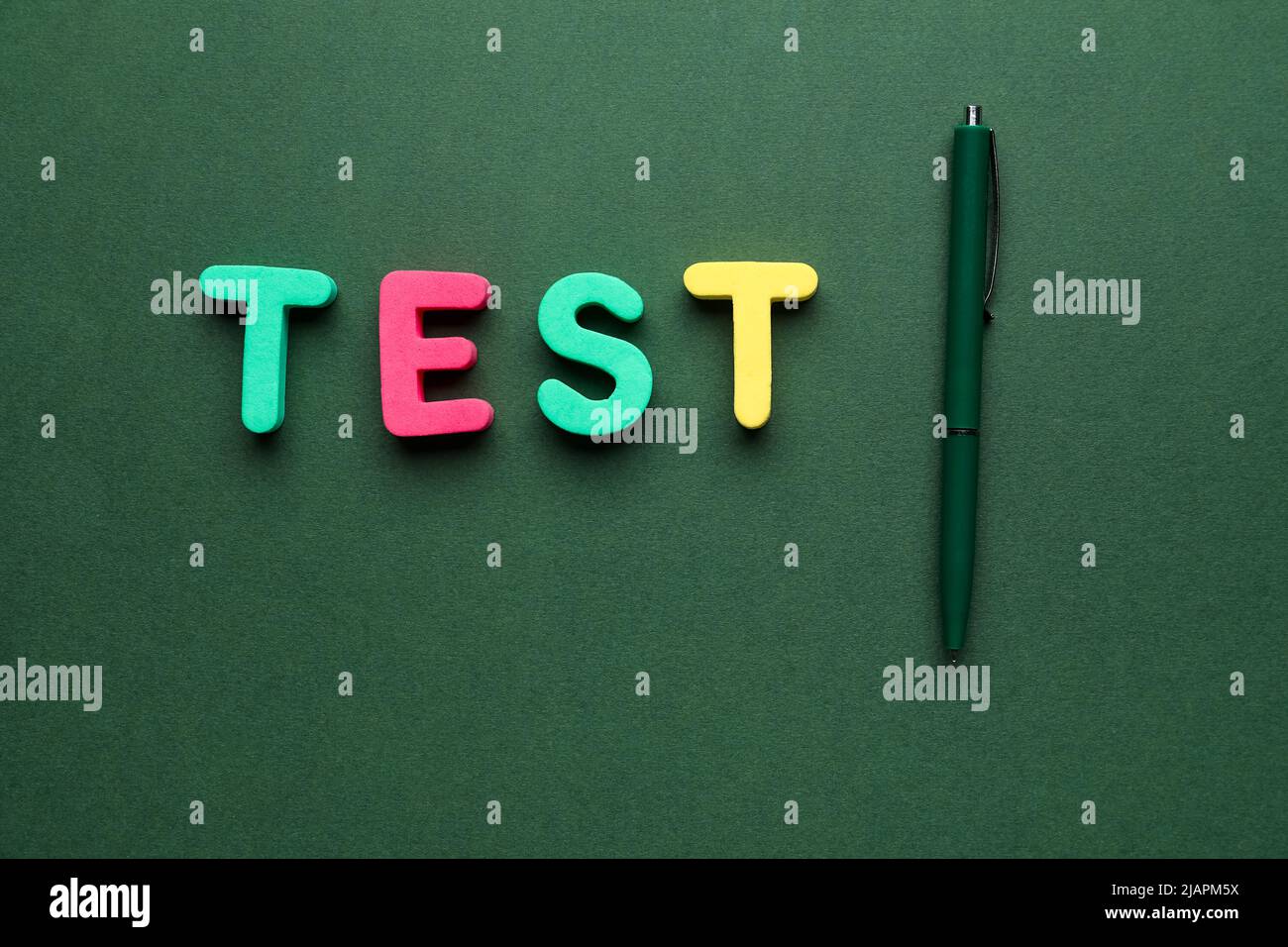 Word TEST with pen on green background Stock Photo - Alamy