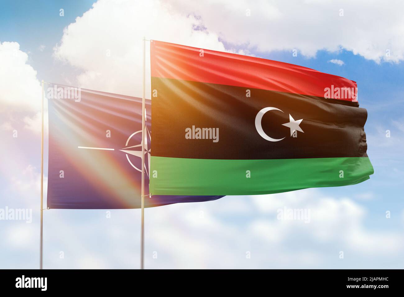 Sunny blue sky and flags of libya and nato Stock Photo - Alamy