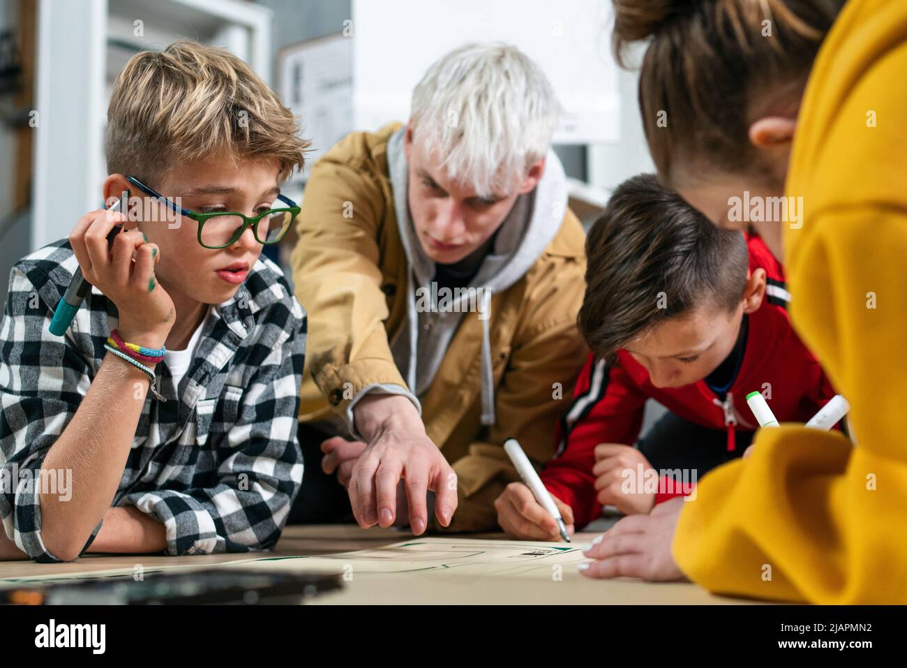 Group of happy kids with their teacher working on project together at ...