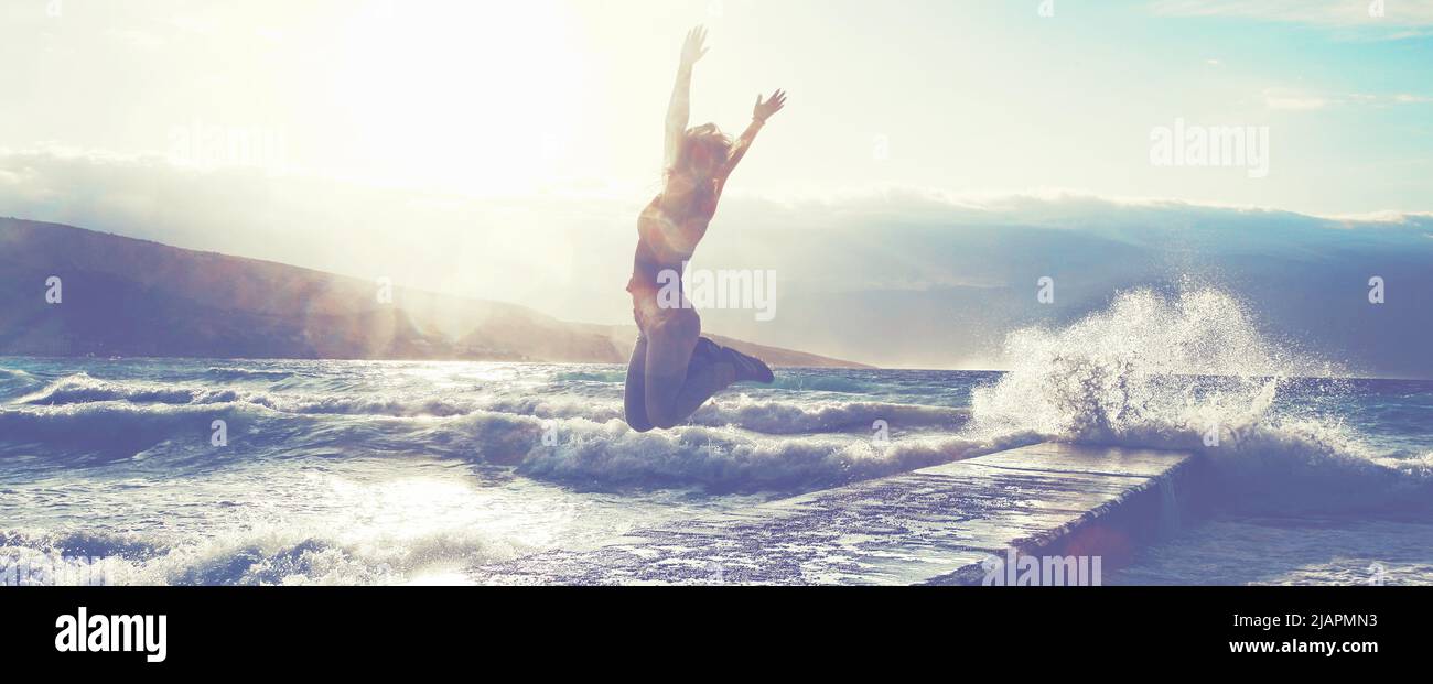 Feeling of freedom concept. Woman jump on pier facing to the sea with ...